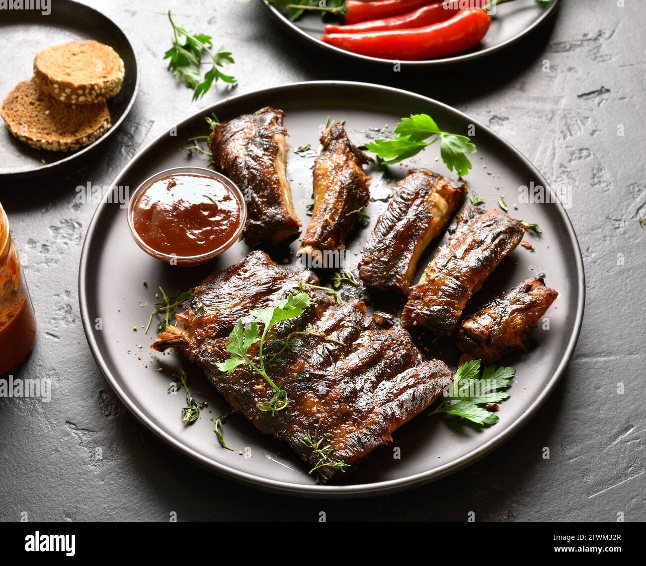 Spicy grilled spare ribs on plate over black stone background. Close up ...