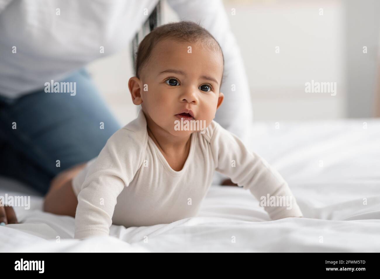 Cute little African American baby crawling in bed with mom Stock Photo ...