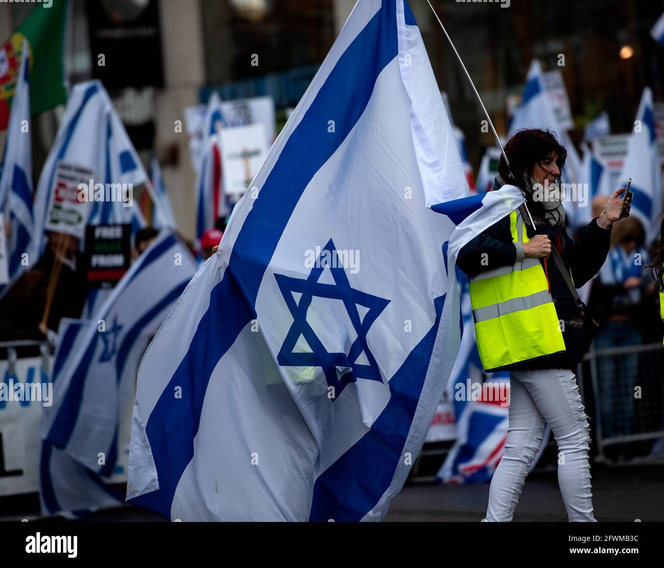 A protester holds a large Israeli flag at the Israeli Embassy on High ...