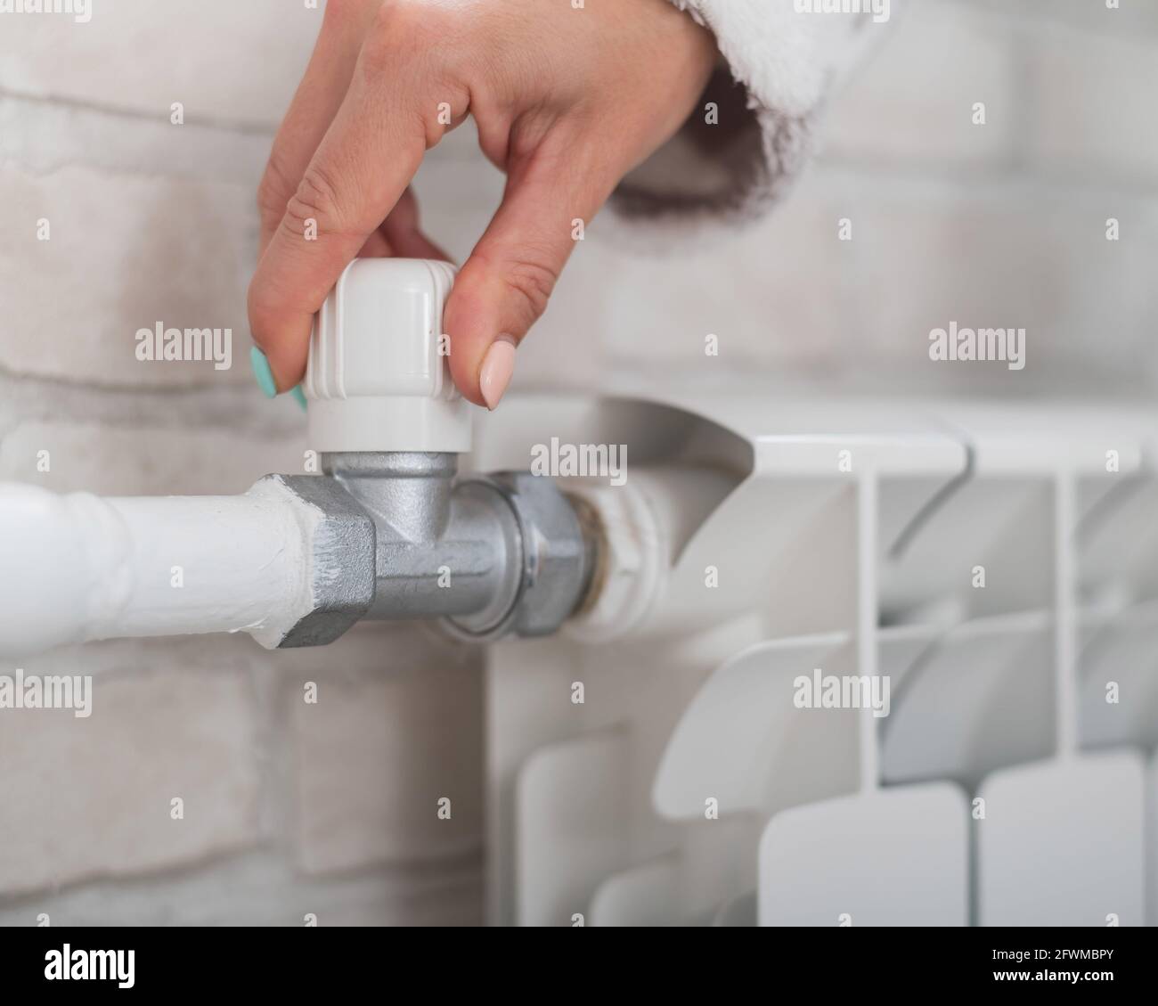 The woman opens the valve of the radiator heating Stock Photo - Alamy
