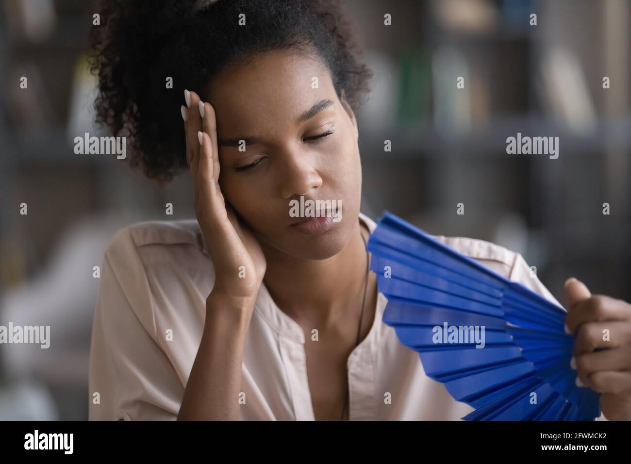 Exhausted overheated young african woman waving paper fan Stock Photo ...