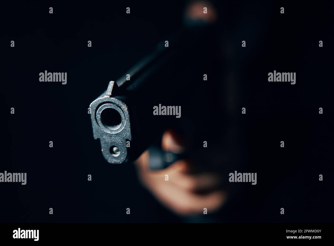 Gun pointed at camera in close-up. Pistol in hand in dark. Criminal ...