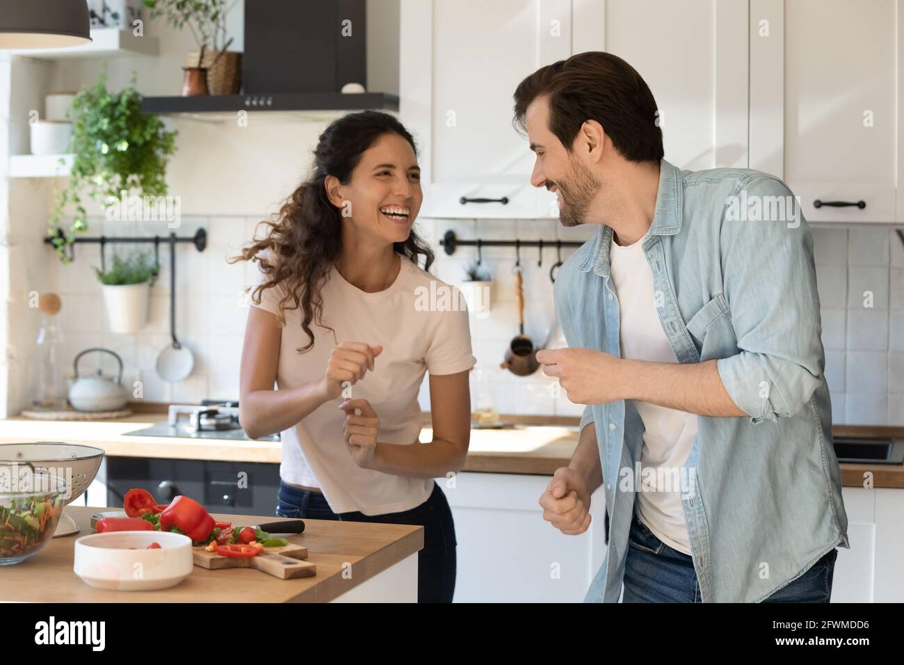 Happy millennial family couple dancing to energetic music in kitchen ...