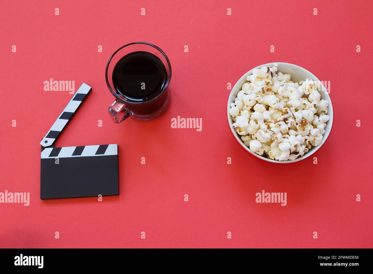 Bowl of popcorn and film clapper isolated on red background. Top view ...