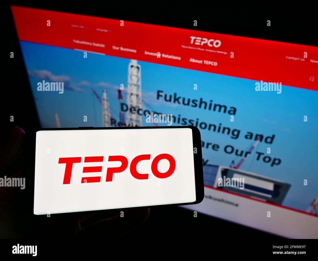 Person holding smartphone with logo of Tokyo Electric Power Company ...