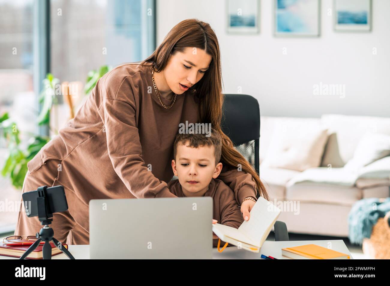 Mother helps her son with online distance education Stock Photo - Alamy