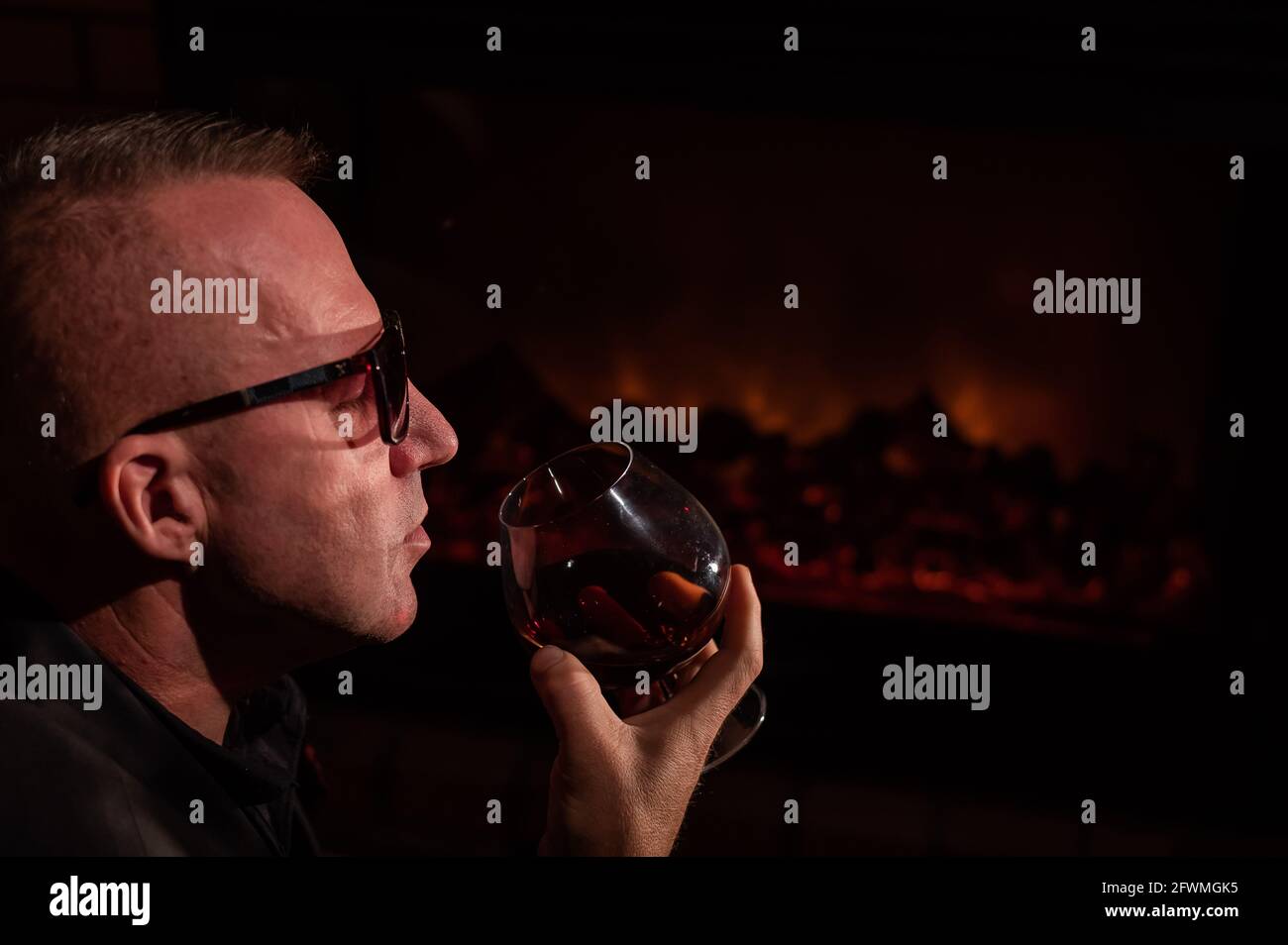 Mature man drinking cognac by the fireplace Stock Photo - Alamy