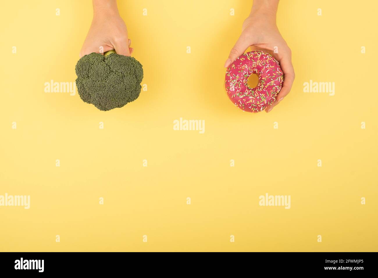 Comparison of eating habits. Woman holding broccoli and donut on a ...
