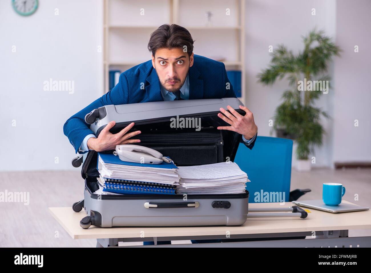 Young businessman employee preparing for business trip at workplace ...