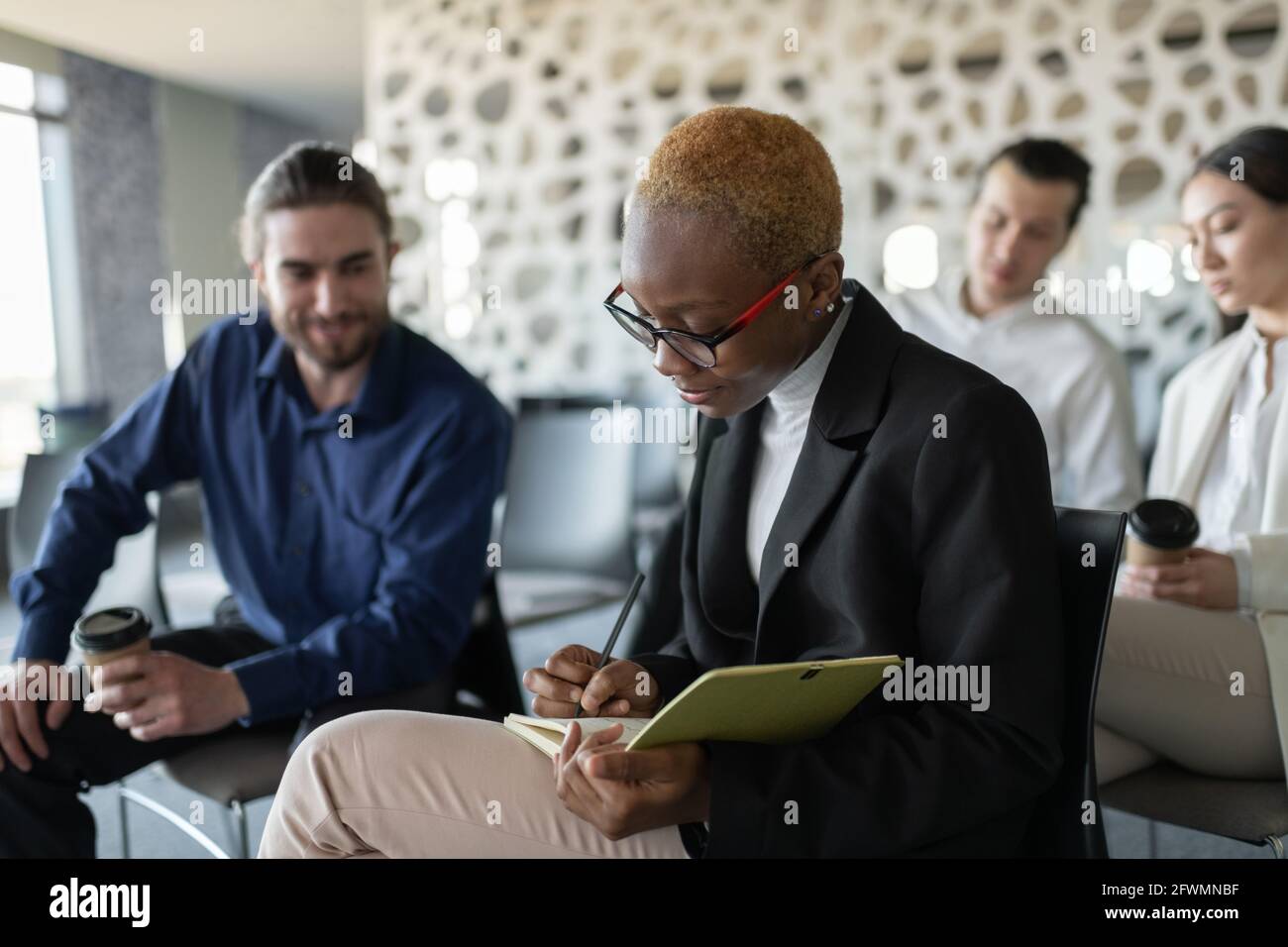 African American woman making notes during conference Stock Photo - Alamy