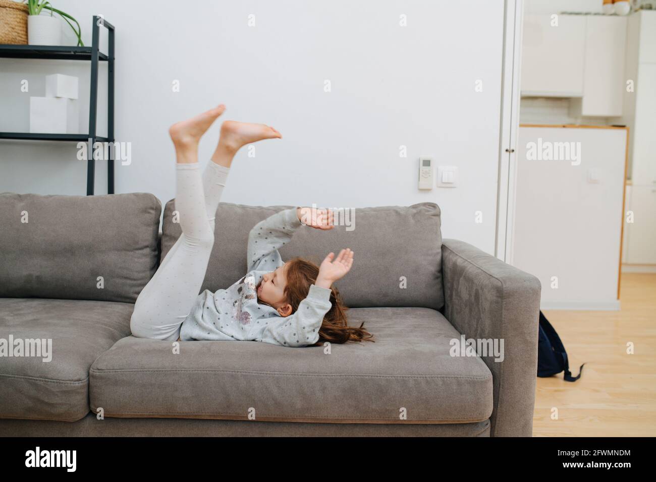 Active little girl rolling backwards on a couch while no one's watching ...