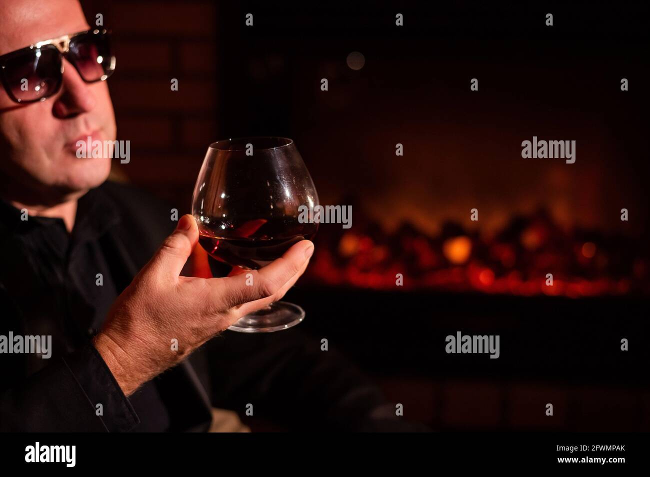Mature man drinking cognac by the fireplace Stock Photo - Alamy