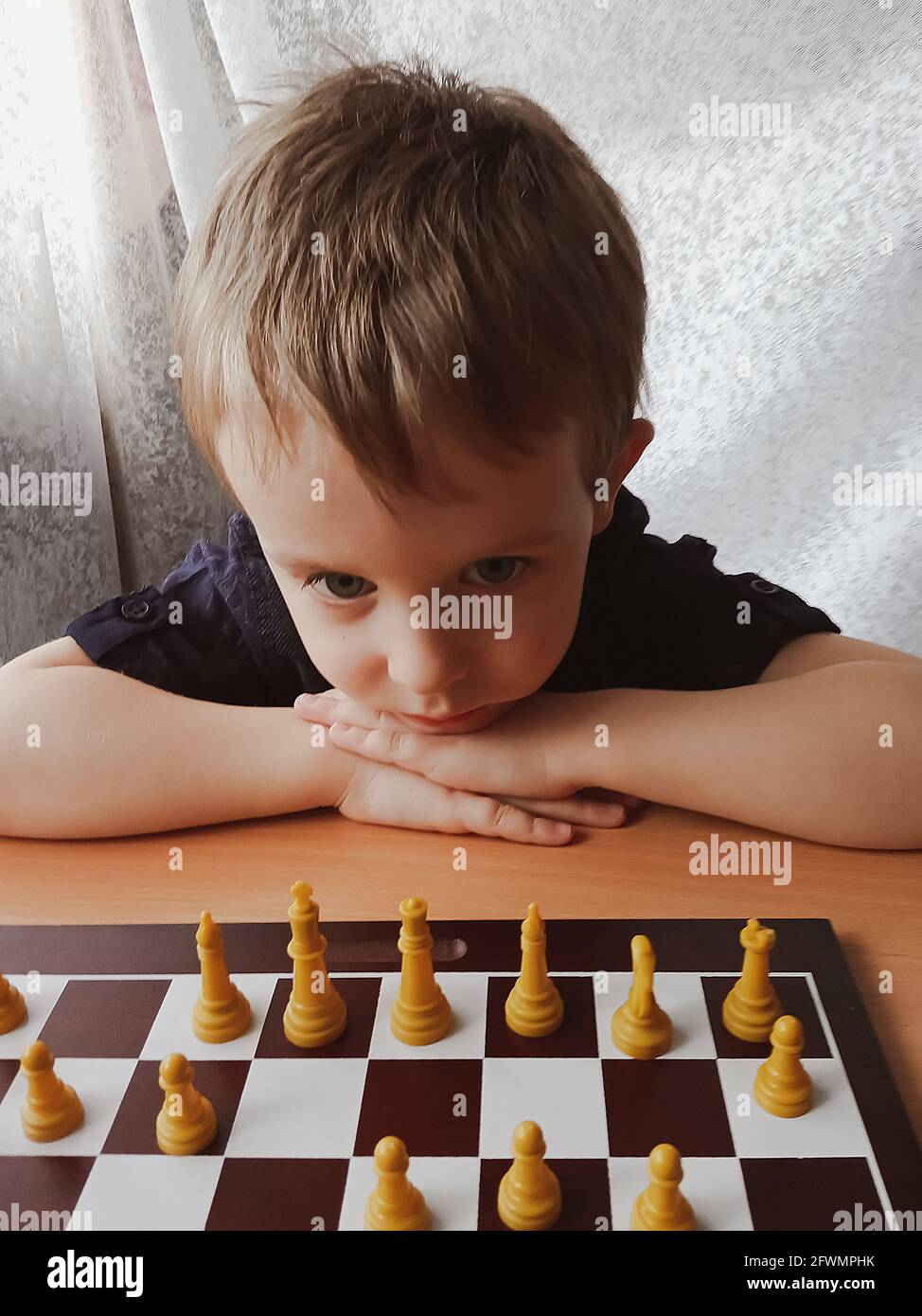 little boy is thinking while playing chess at home. leisure Stock Photo ...
