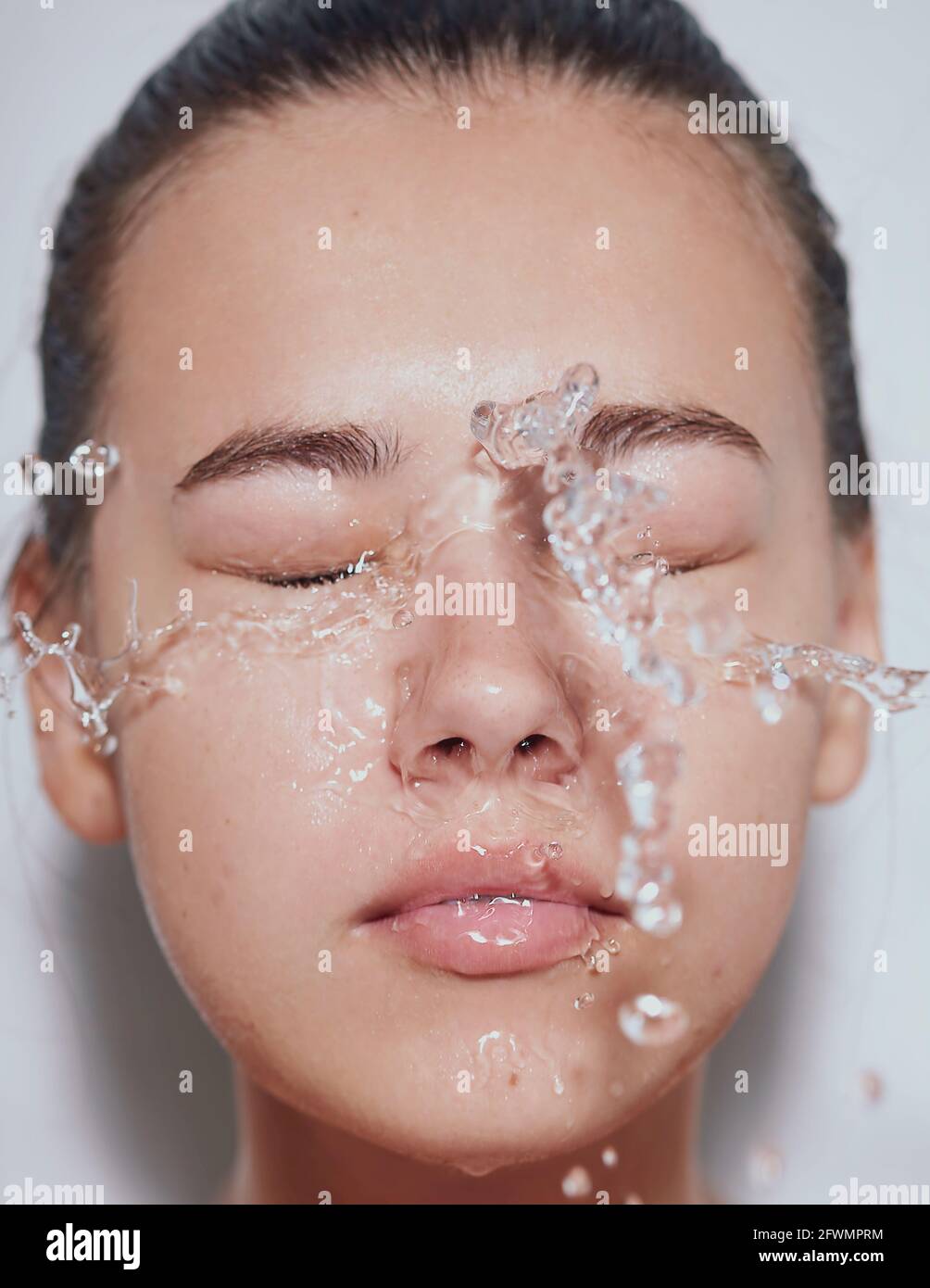 Young beautiful woman with clean fresh skin with splash of water ...