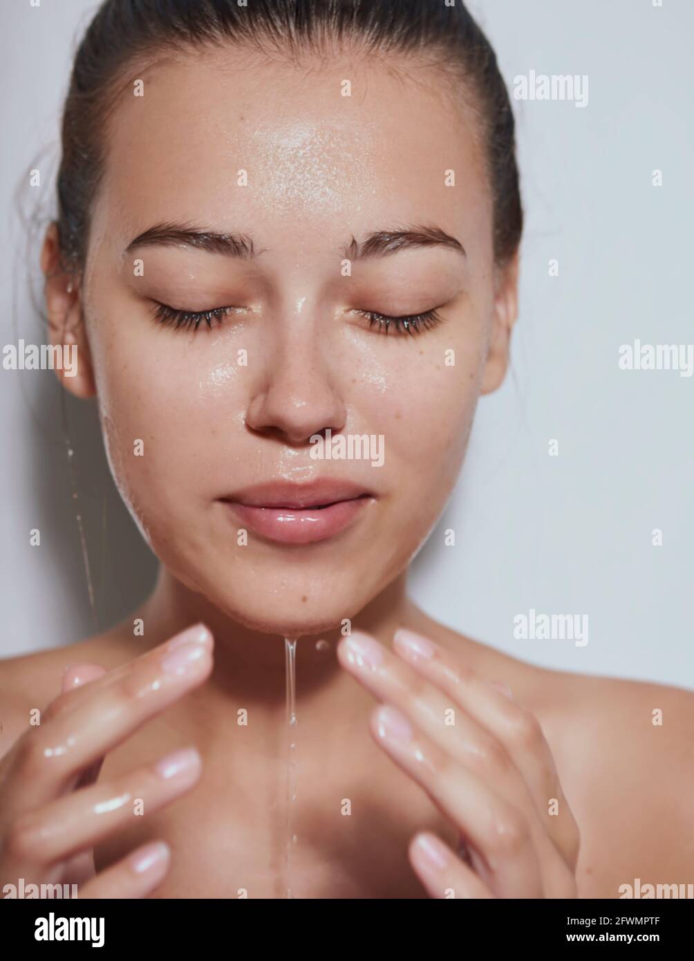 Young beautiful woman with clean fresh skin with splash of water ...