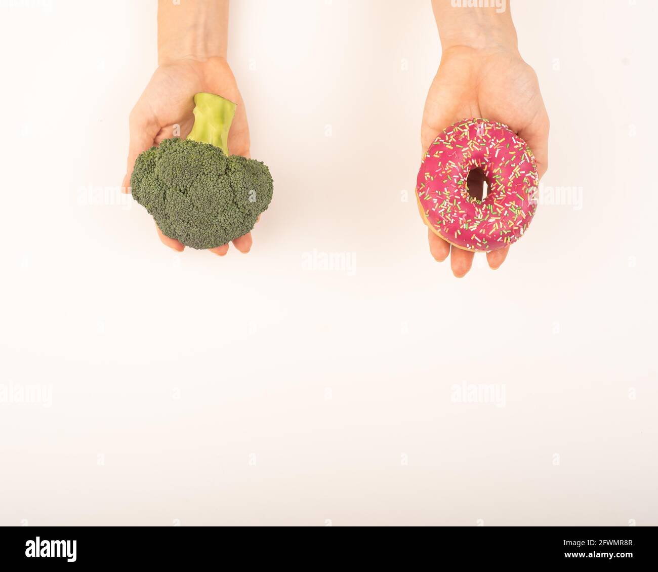 Comparison of eating habits. Woman holding broccoli and donut on a ...