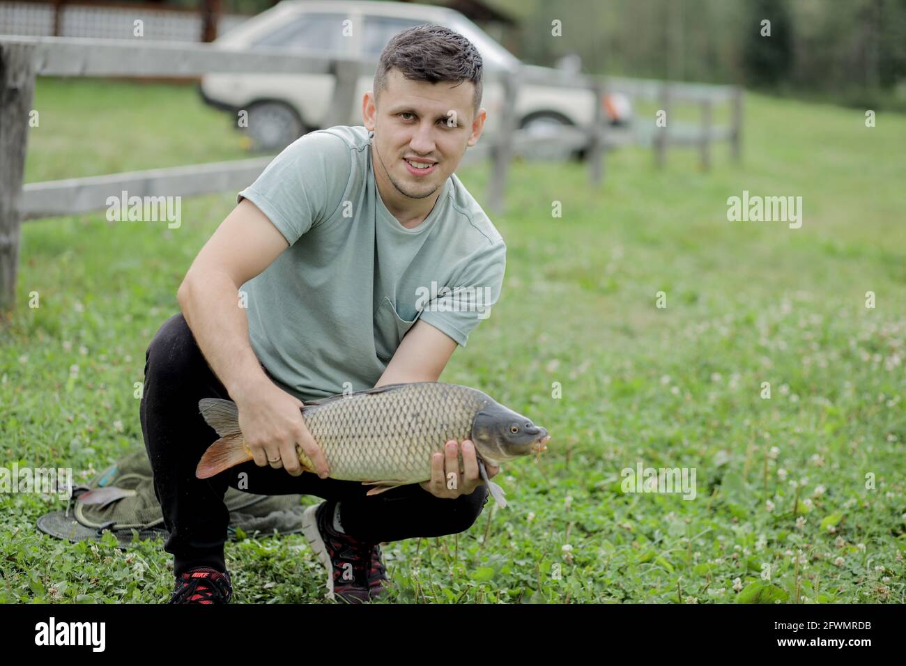 Happy angler holds trophy carp. Man with carp fish. Outdoors activities ...