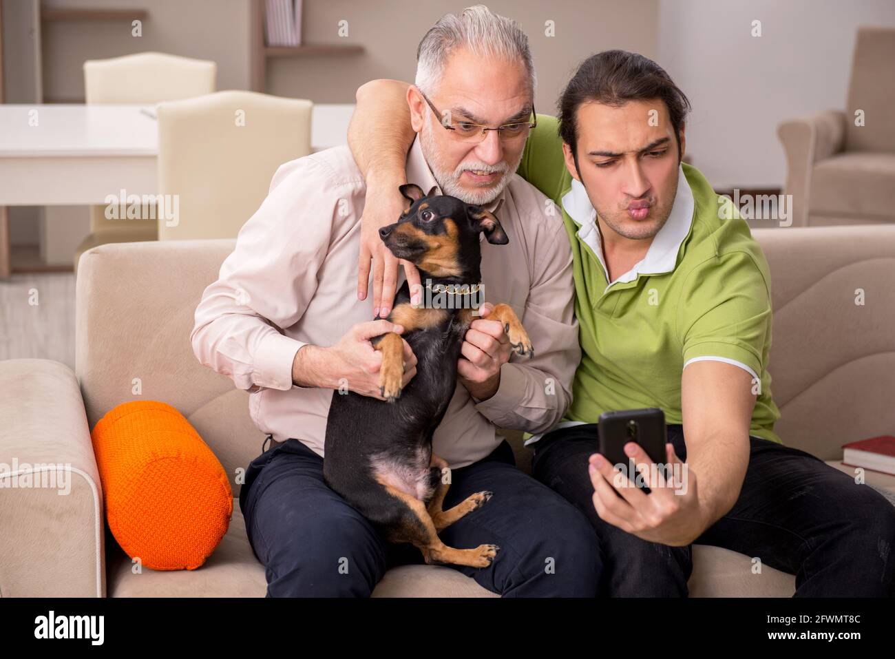 Two men with dog in the room Stock Photo - Alamy
