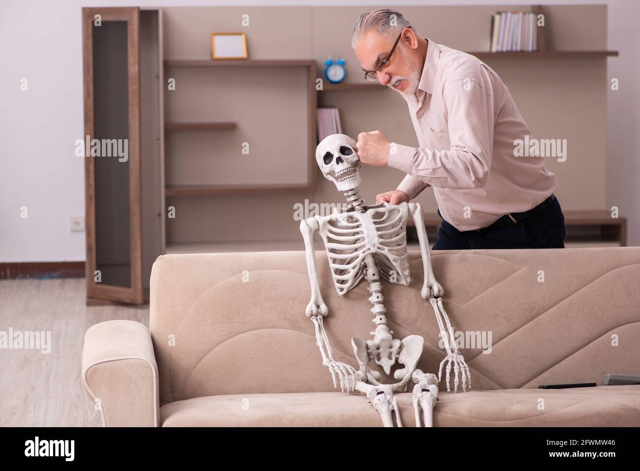 Old man sitting on the sofa with the female skeleton in undying love ...