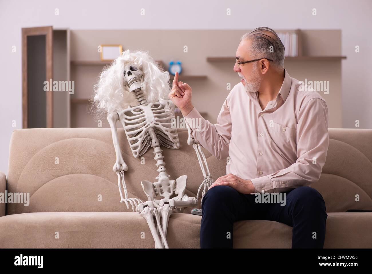 Old man sitting on the sofa with the female skeleton in undying love ...