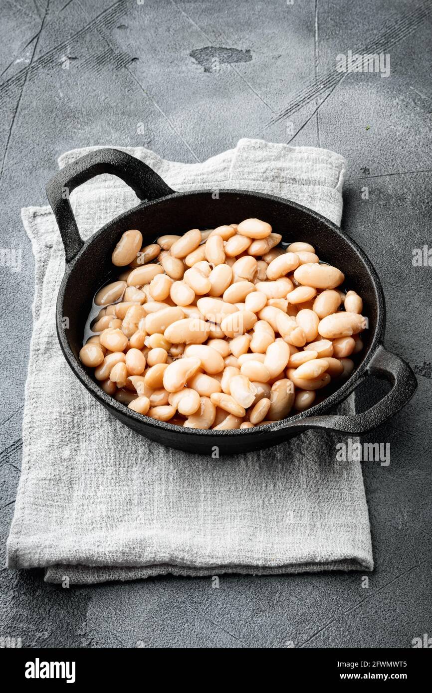 Canned white beans set, in cast iron frying pan, on gray stone ...