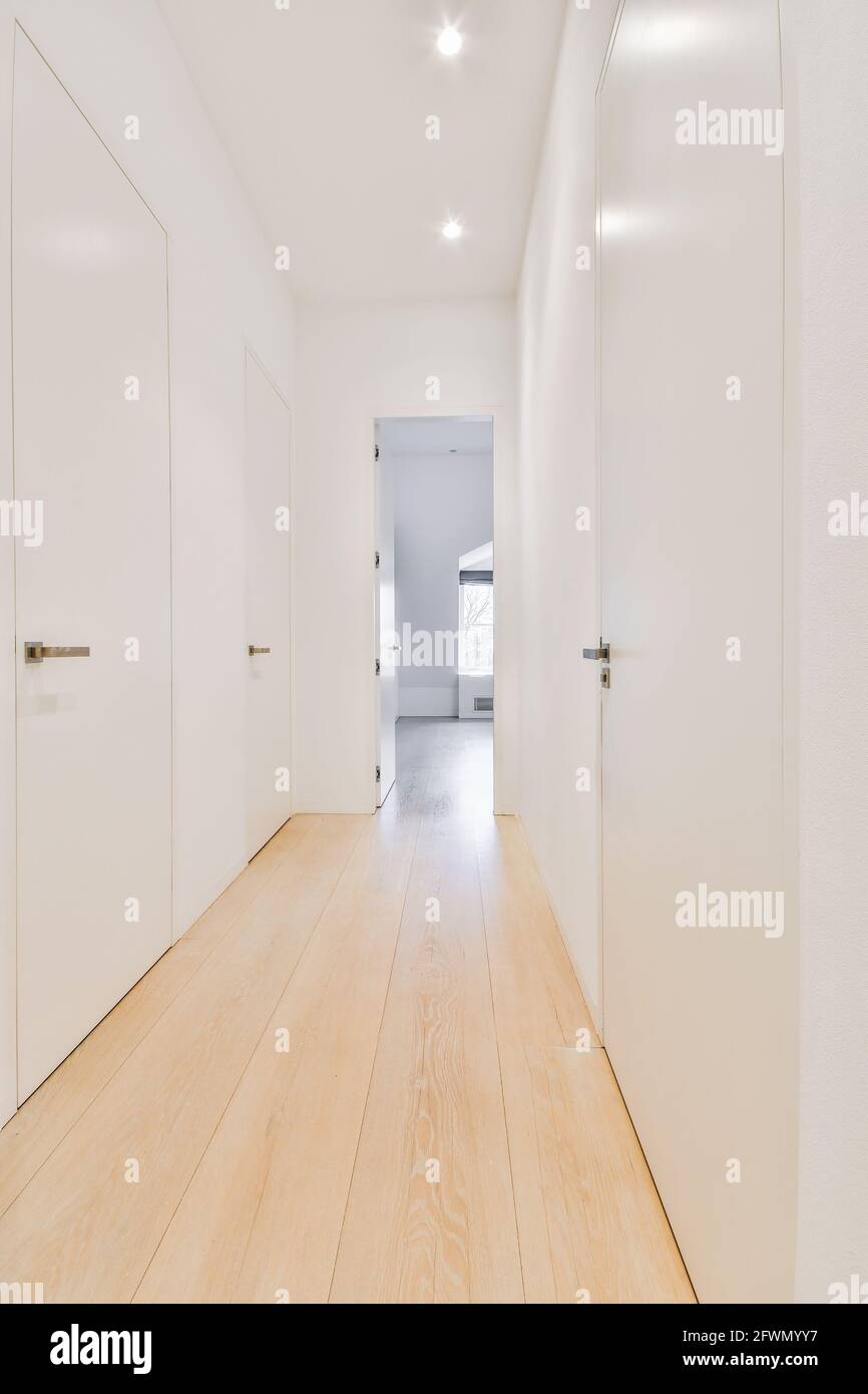 Perspective view of flat long hallway with white walls and doors and ...