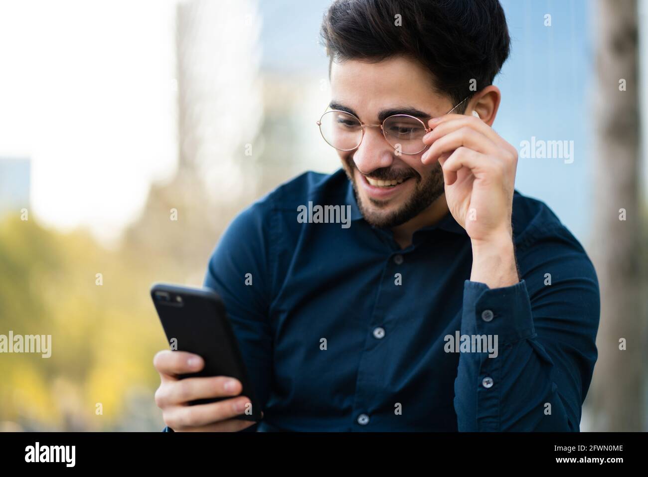 Young man using his mobile phone outdoors Stock Photo - Alamy