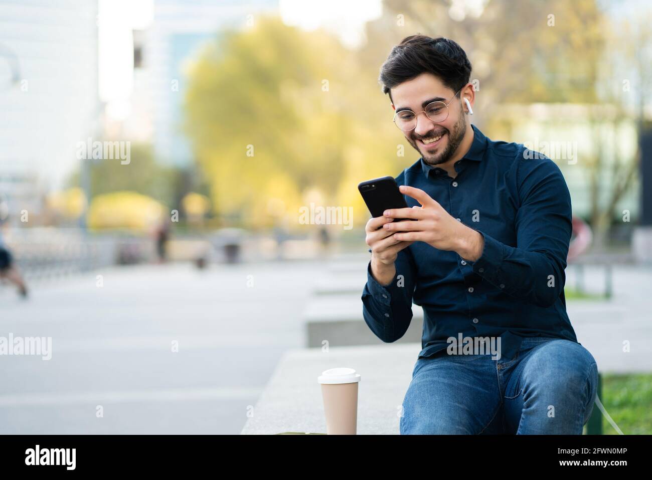 Young man using his mobile phone outdoors Stock Photo - Alamy