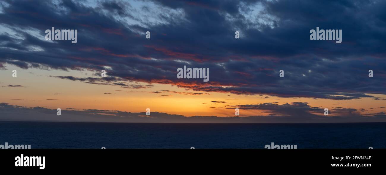 An evening cloudscape panorama with vivid colors in the sky and dark ...