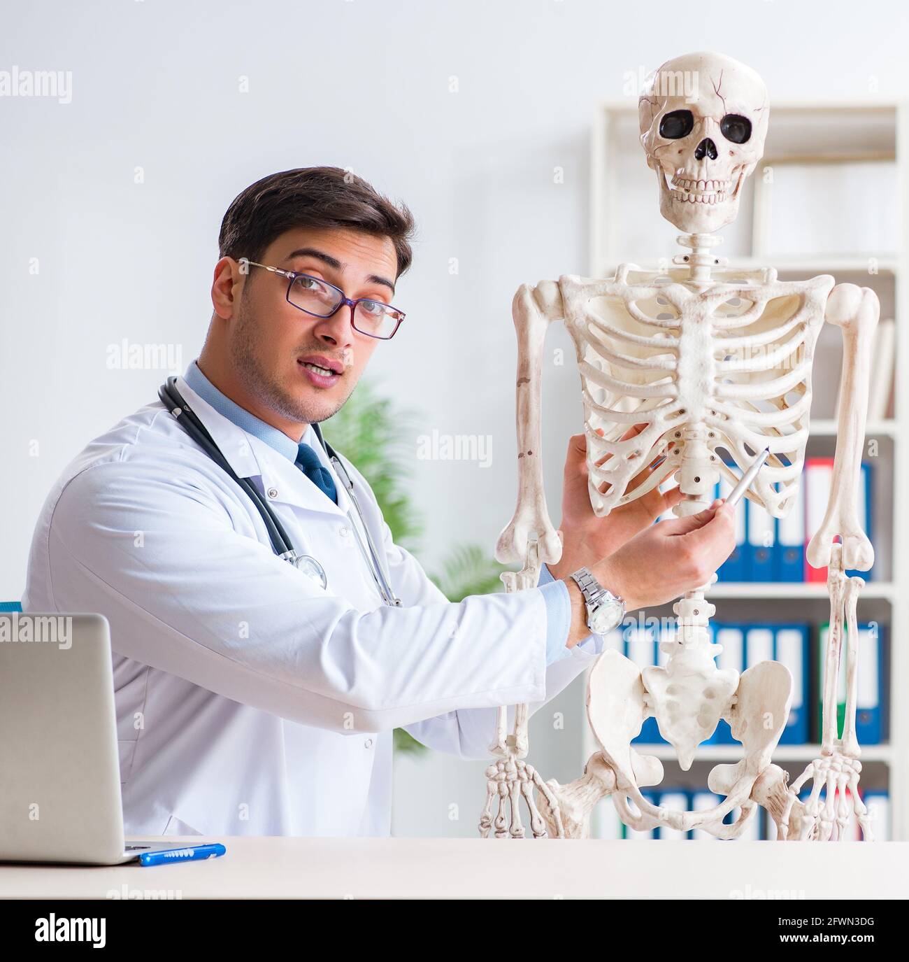 The yong male doctor with skeleton isolated on white Stock Photo - Alamy