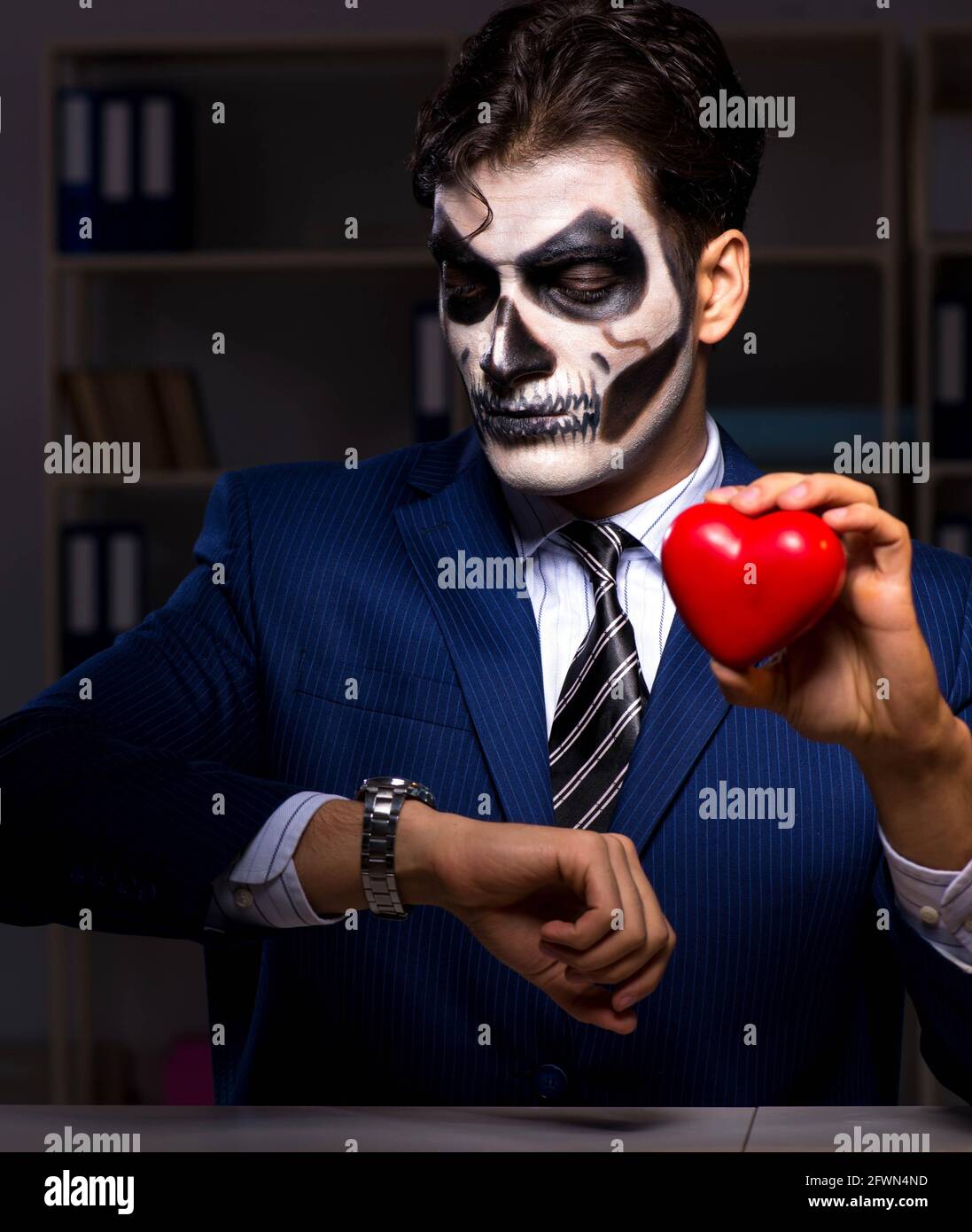 The businessman with scary face mask working late in office Stock Photo ...