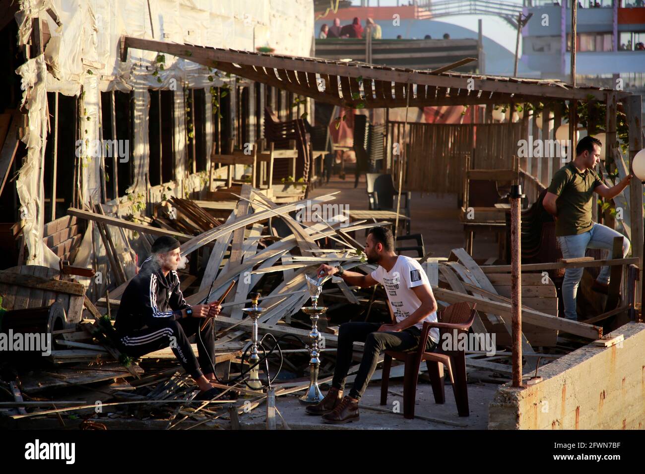 Palestinians smoke a water pipe at the side of Israeli airstrike in ...