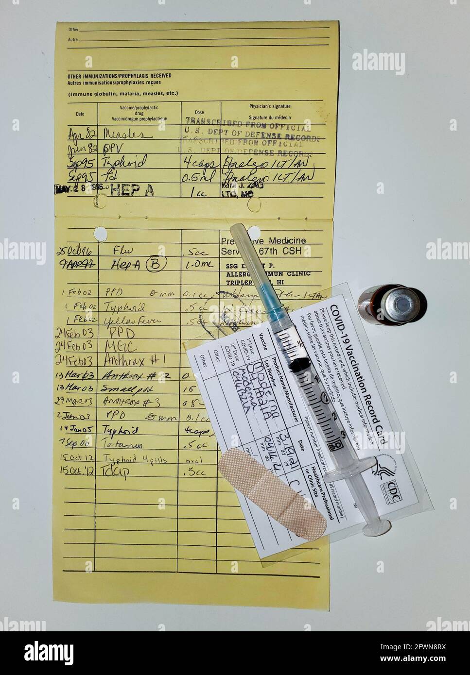 Vaccination record with syringe and vial of Covid vaccine with adhesive ...
