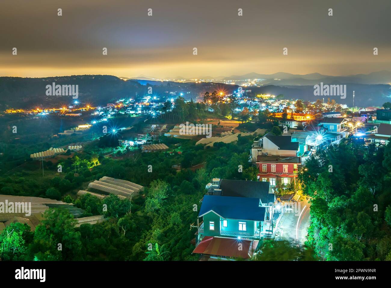 Night scene in the valley with bright houses with colorful lights makes ...