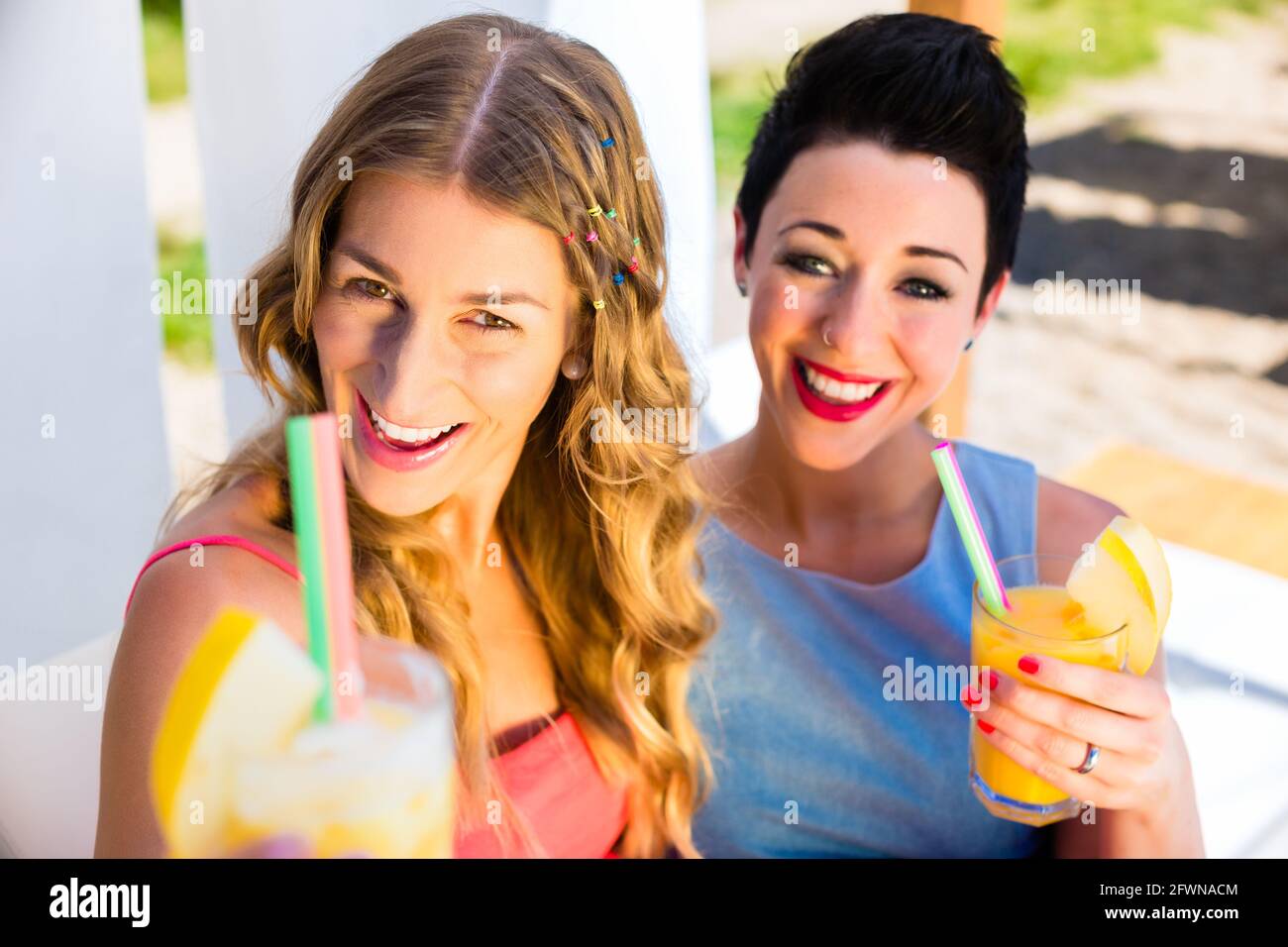 Two friends at lake beach with drinks relaxing Stock Photo - Alamy