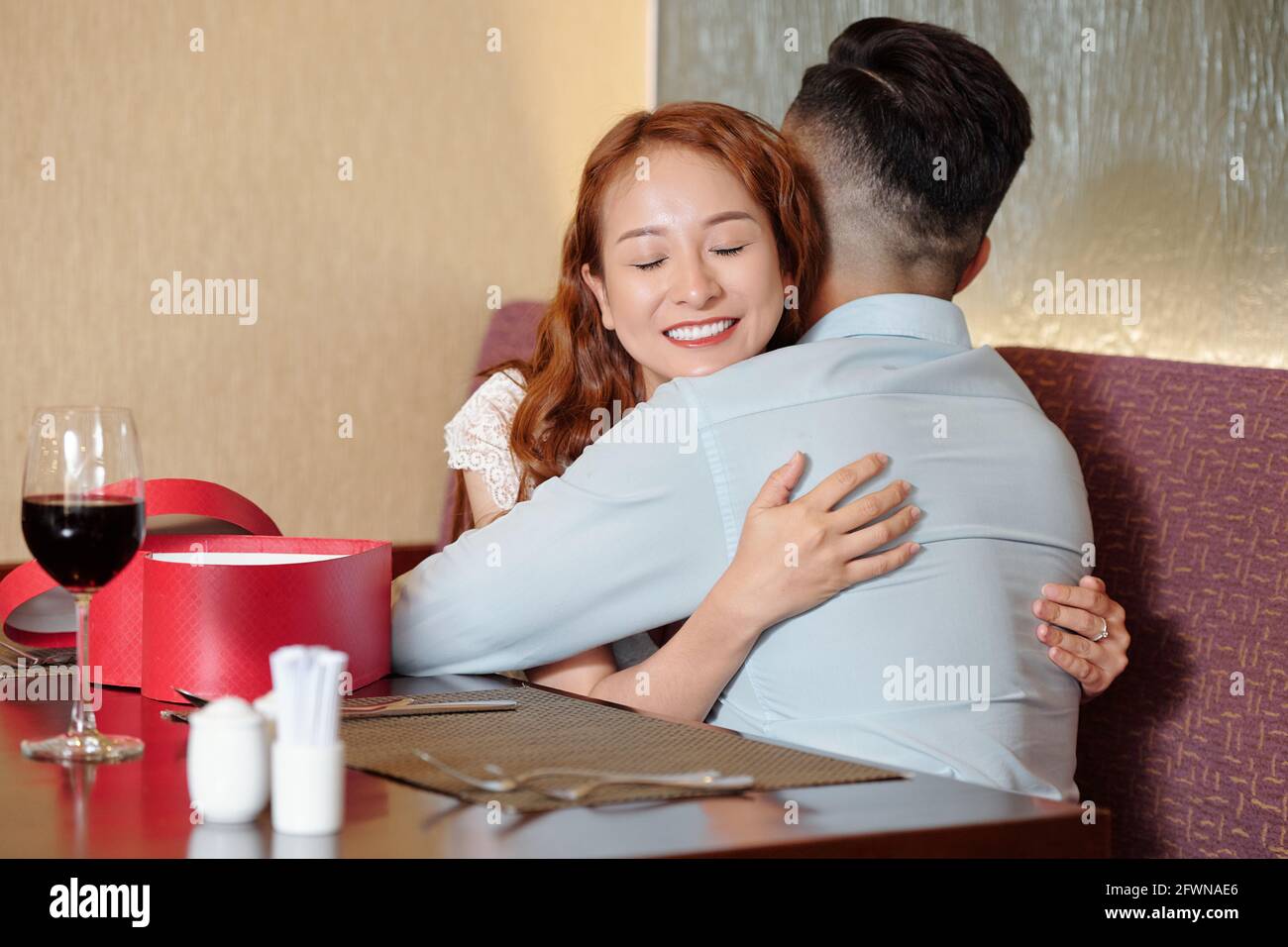 Happy pretty young woman hugging her boyfriend after receving birthday present Stock Photo - Alamy
