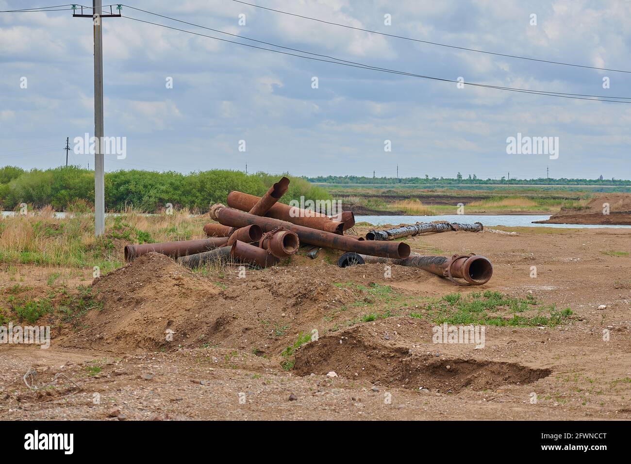 a bunch of rusty pipes lies in the grass against the background of the ...