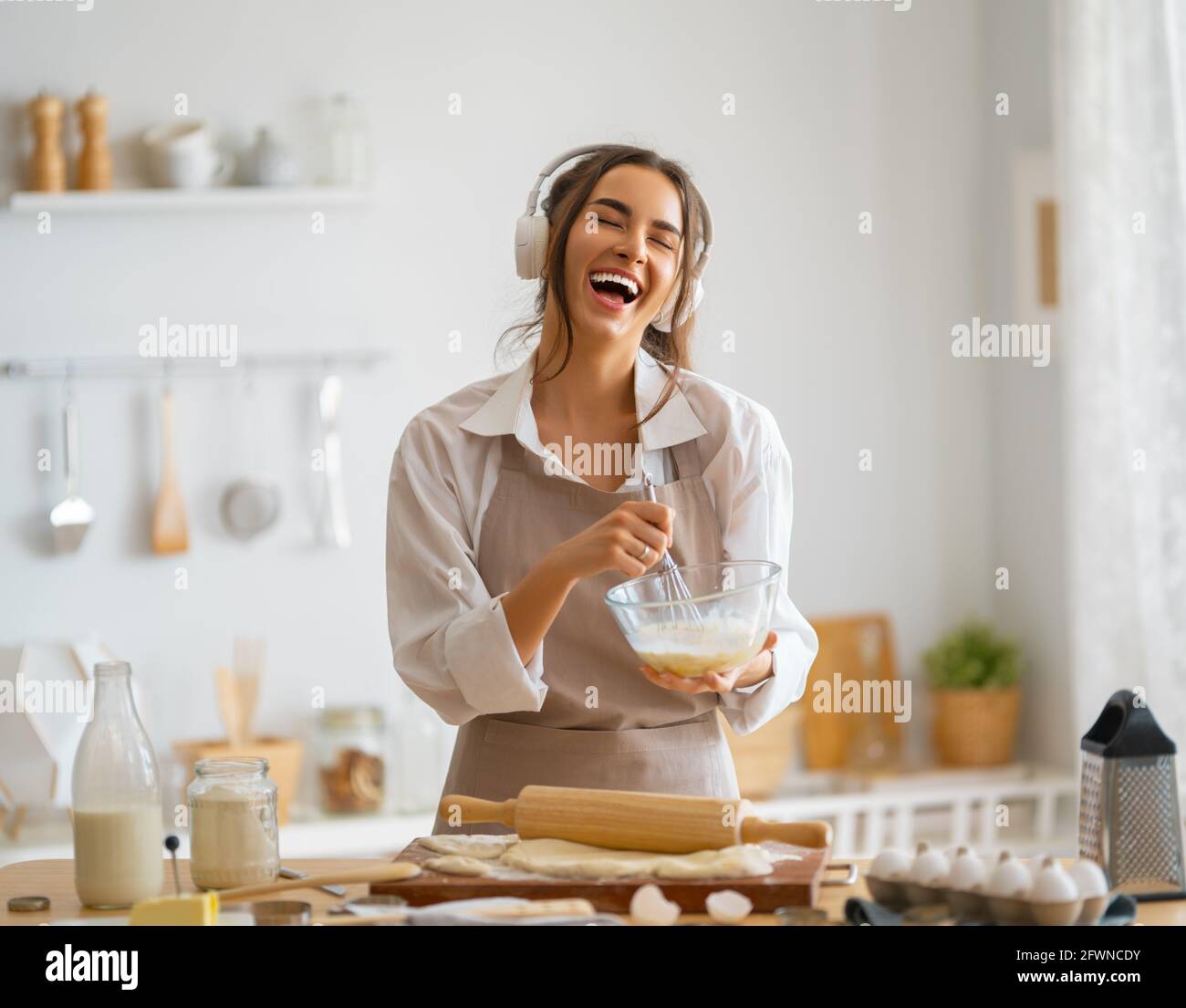 Happy woman is preparing bakery. Girl is cooking cookies in the kitchen ...