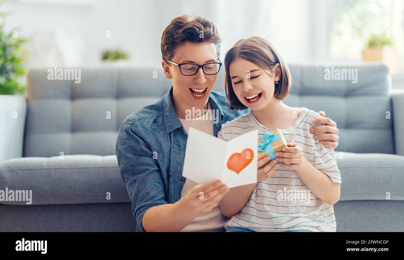 Child daughter is congratulating her father and giving him postcard ...