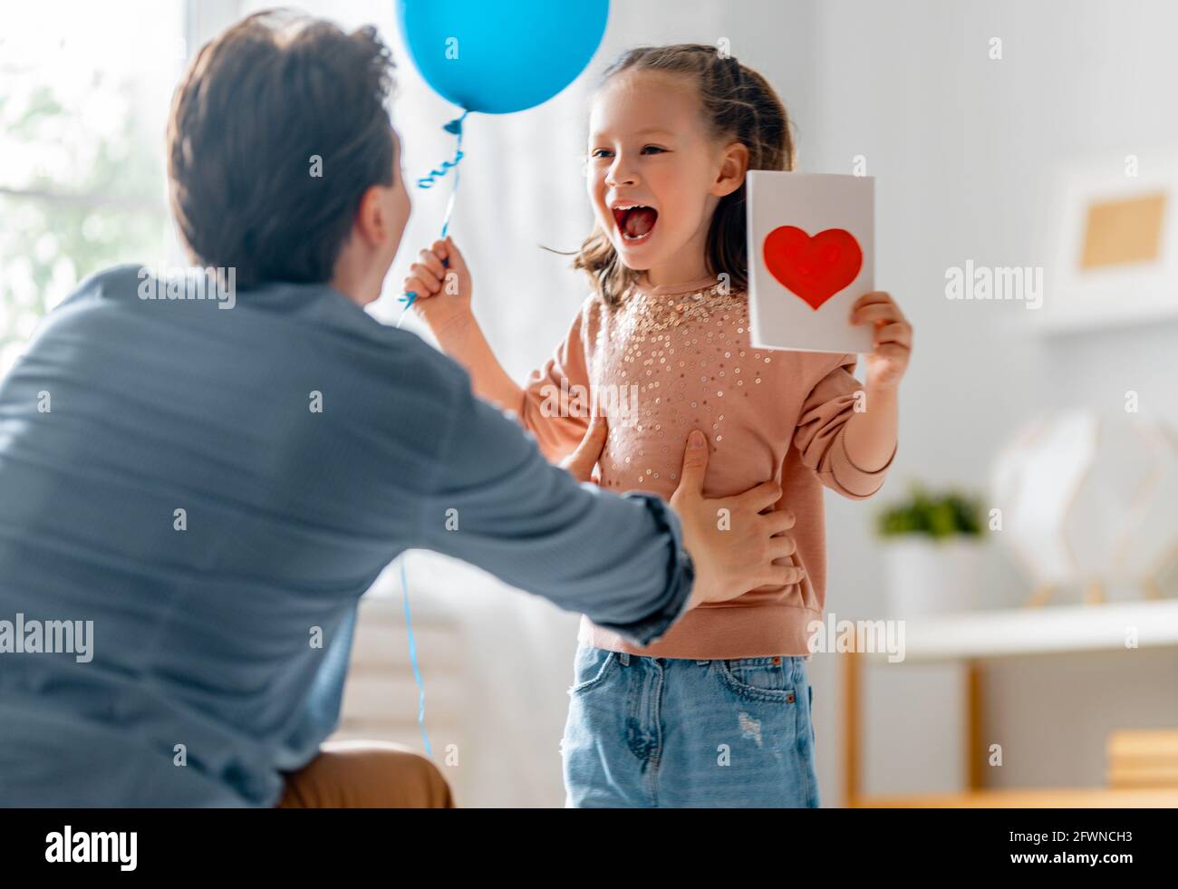 Child daughter is congratulating her father and giving him postcard ...