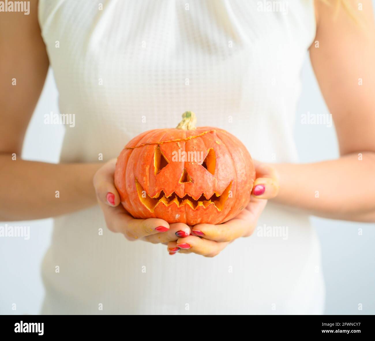 Female hands holding a pumpkin for Halloween. Close-up of a woman opens ...