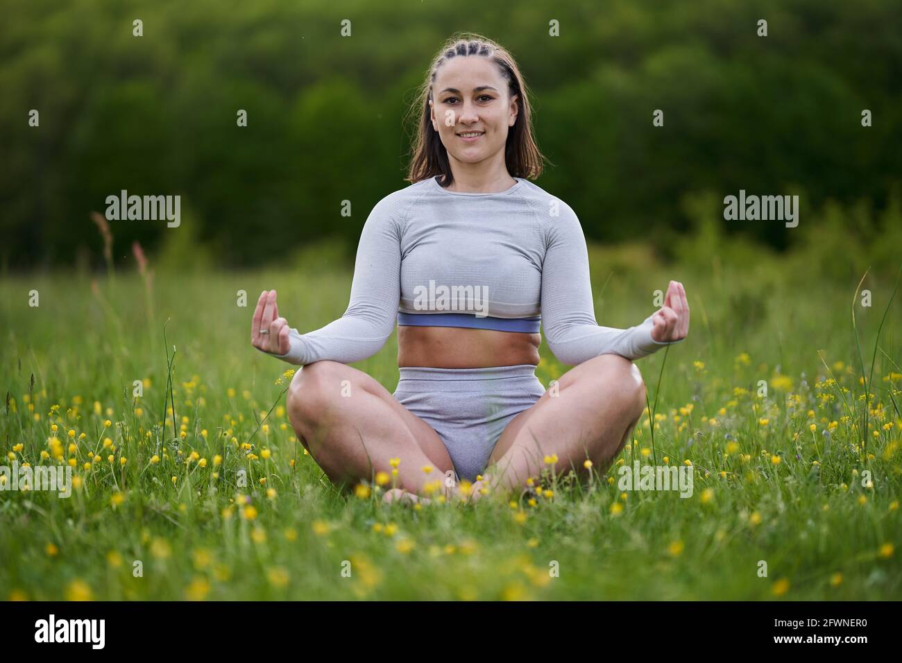 Confident beautiful plus size woman doing yoga in a field by the forest ...