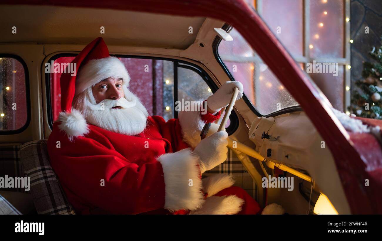 Portrait of santa claus driving a car loaded with a Christmas tree and ...