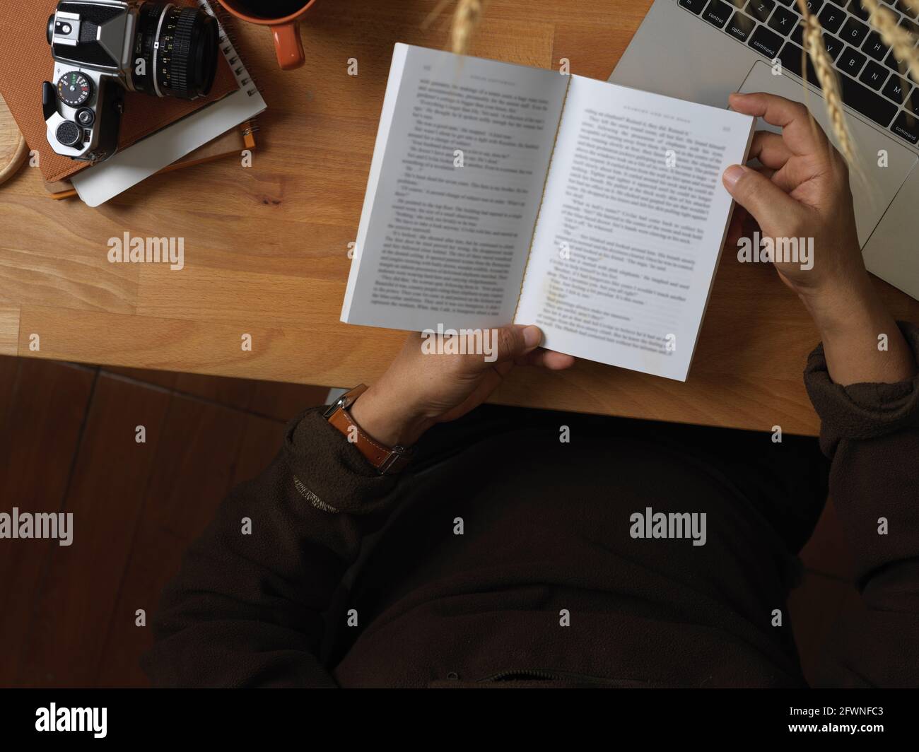 Top view of male reading book on wooden worktable in home office room ...