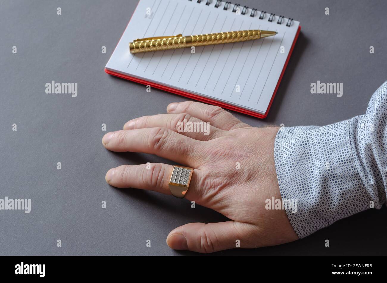 Hand, notepad, gold pen on gray background. Adult man with a seal on ...