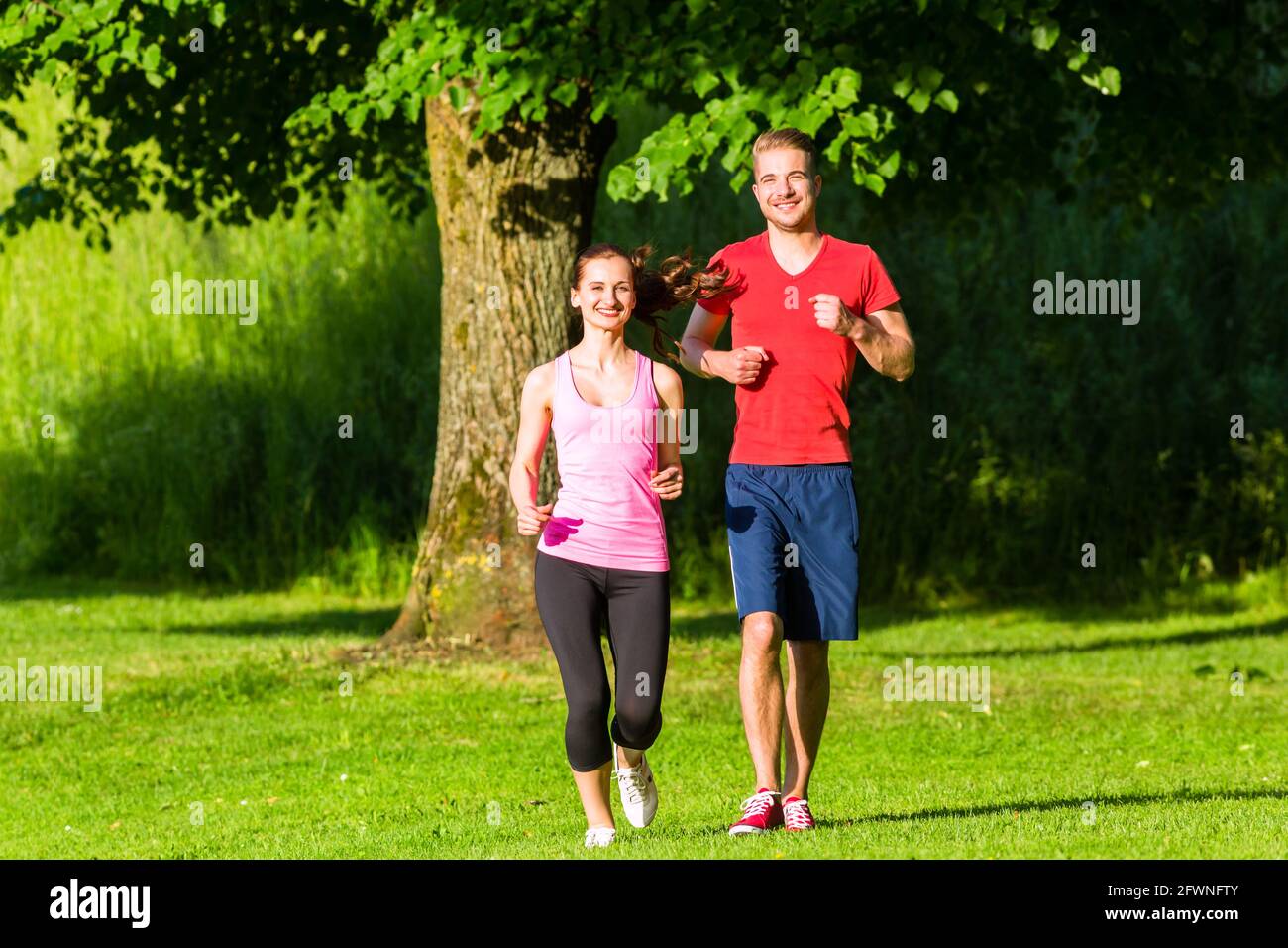 Fitness Friends running together through park Stock Photo - Alamy