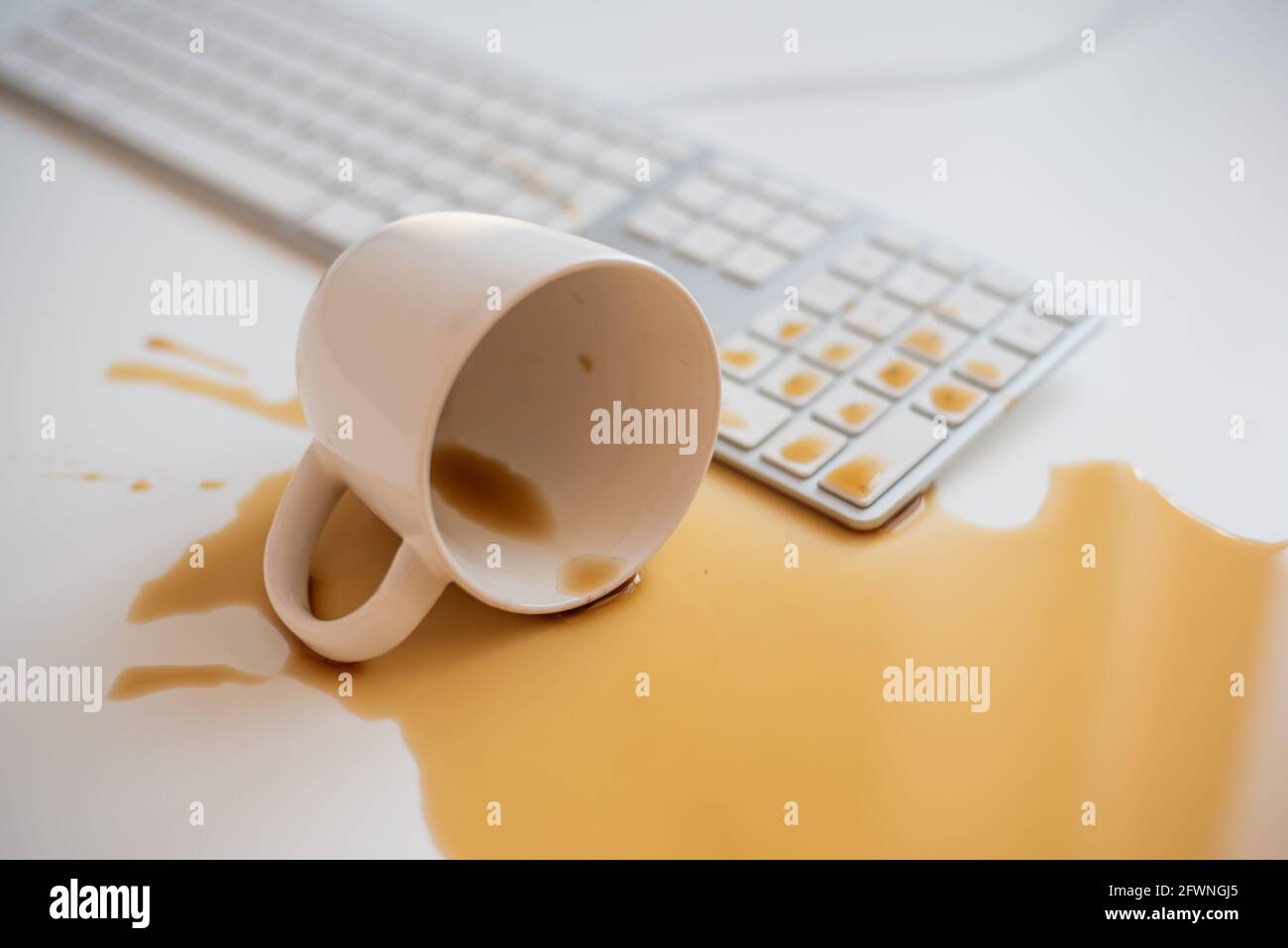 Spilled black coffee on a computer keyboard at a white table Stock ...
