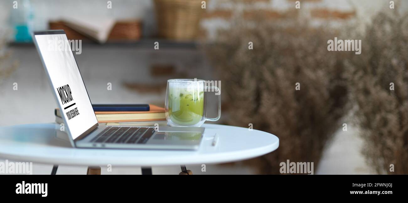 Side view of portable workspace with laptop, stationery and matcha ...
