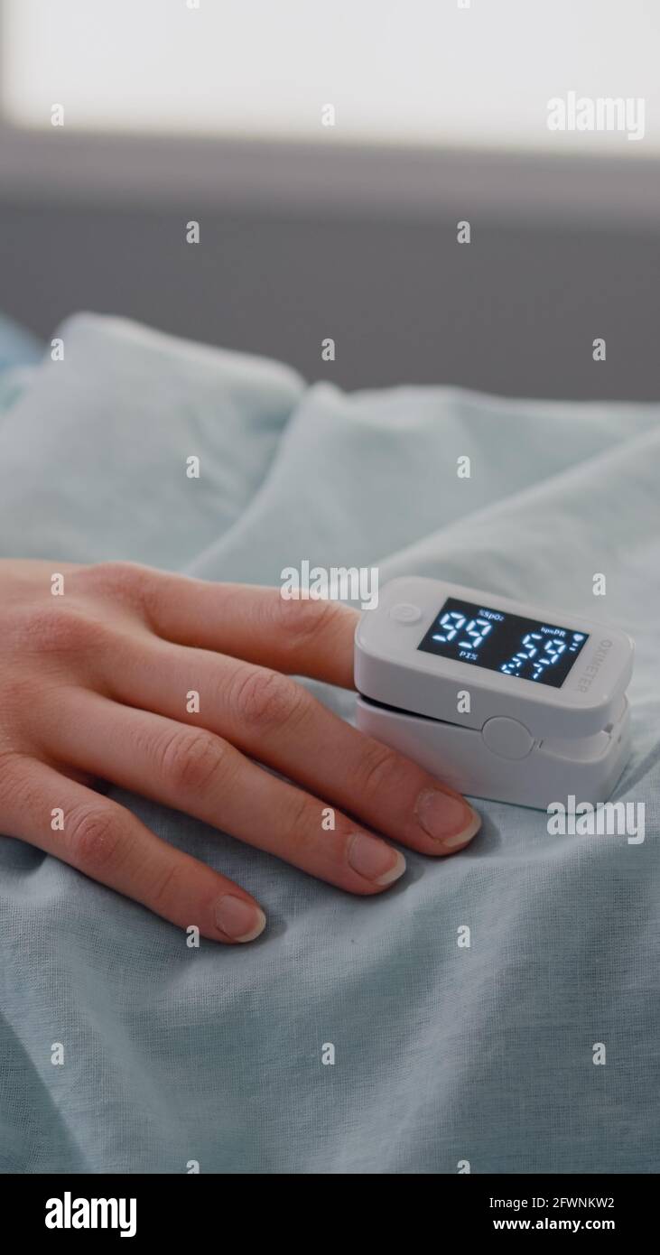 Close up of sick woman resting in bed in hospital ward with finger ...
