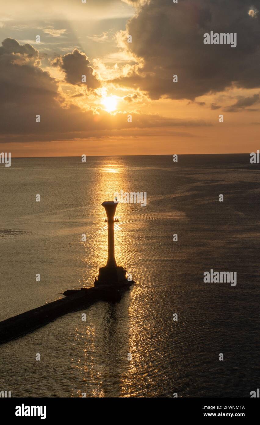 Lighthouse at dusk, ships pass through the harbor Stock Photo - Alamy